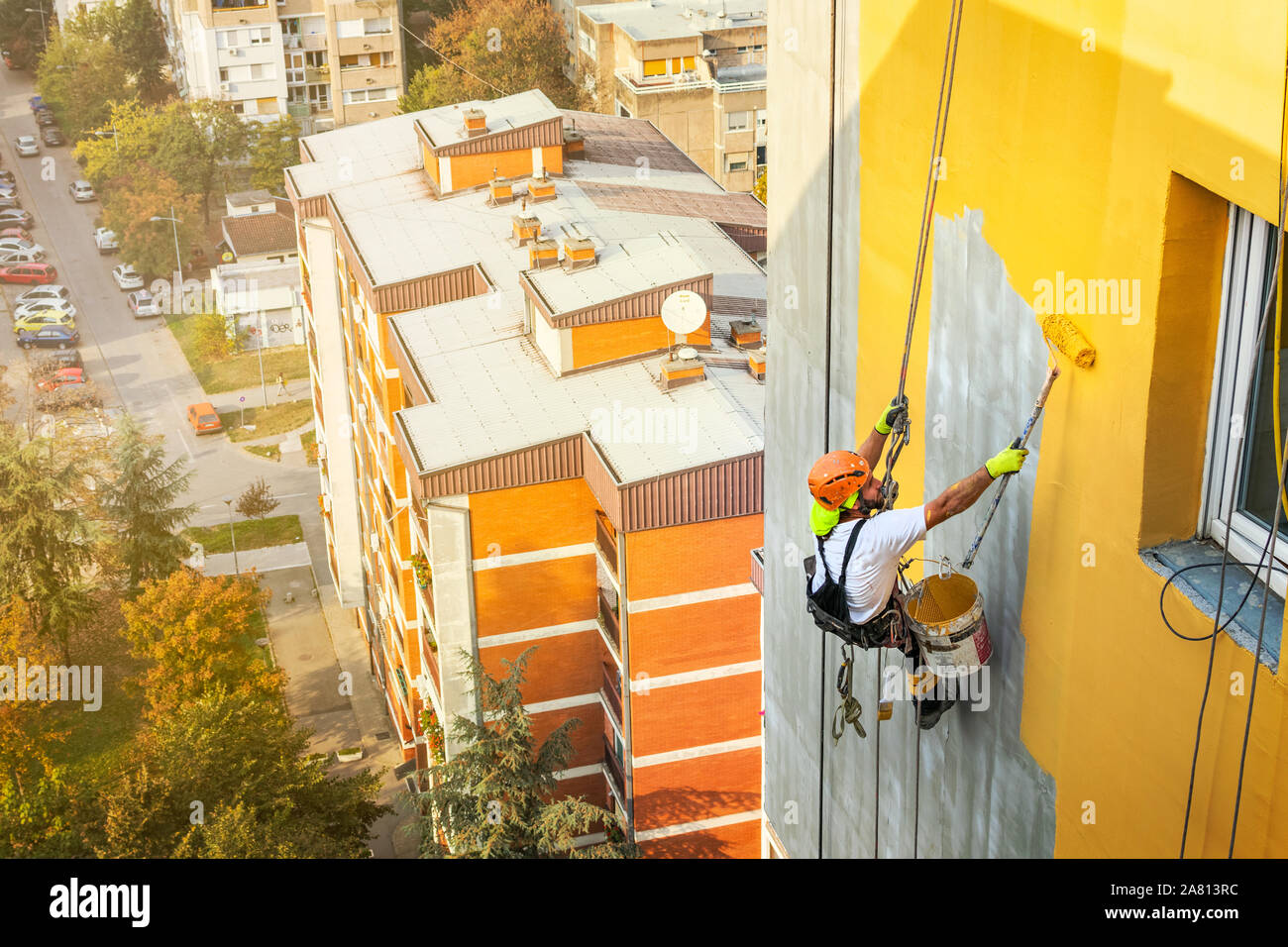 Industrial rope access worker hanging from the building while painting ...