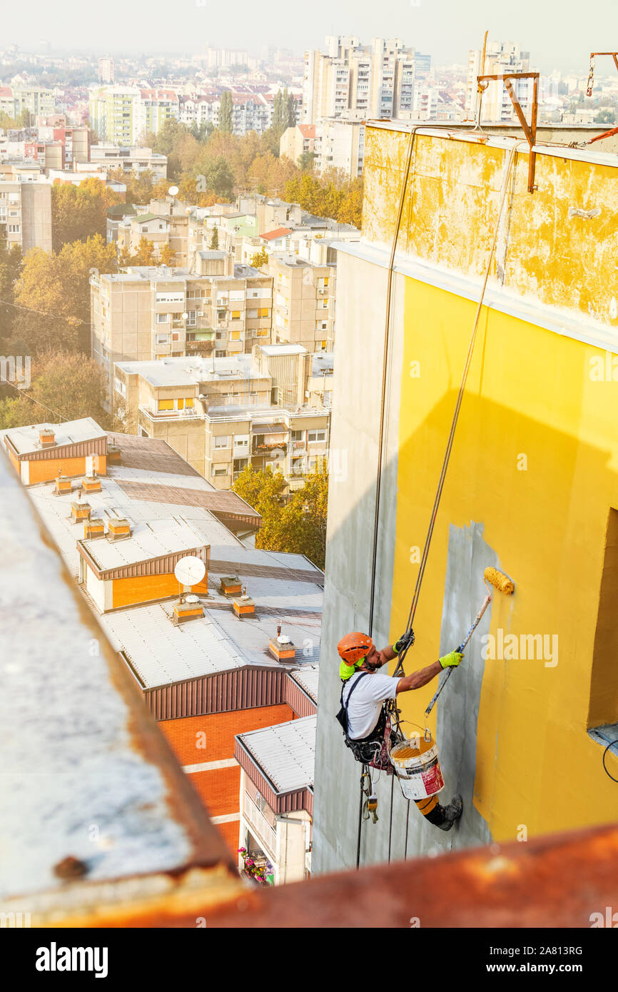 Industrial rope access worker hanging from the building while painting ...