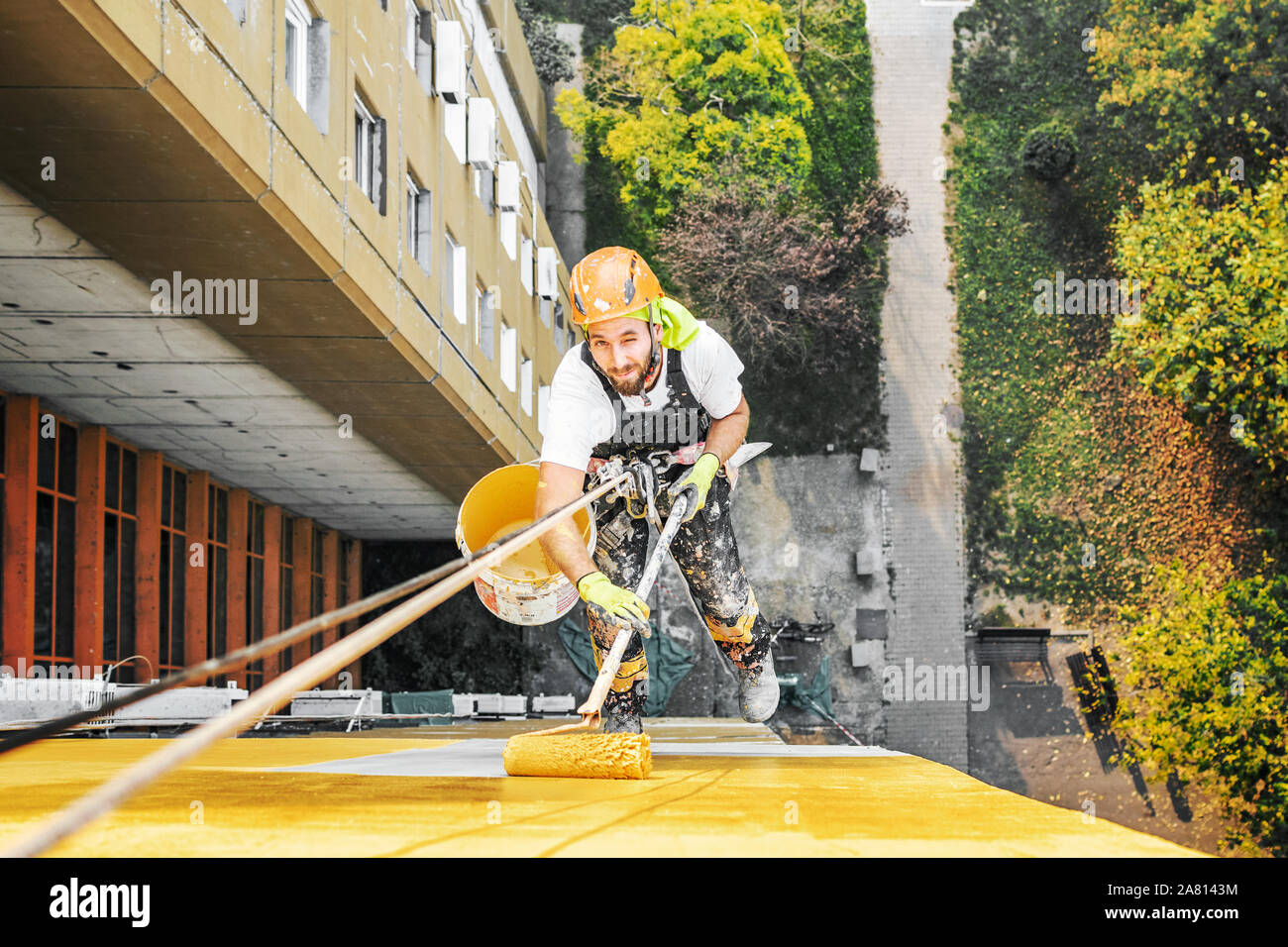 Industrial rope access worker hanging from the building while painting ...
