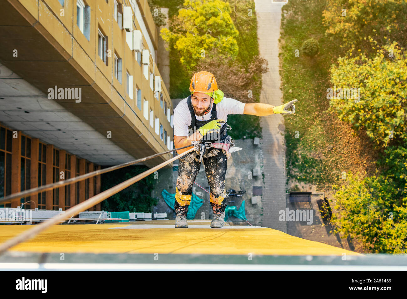 Industrial rope access worker hanging from the building while painting ...
