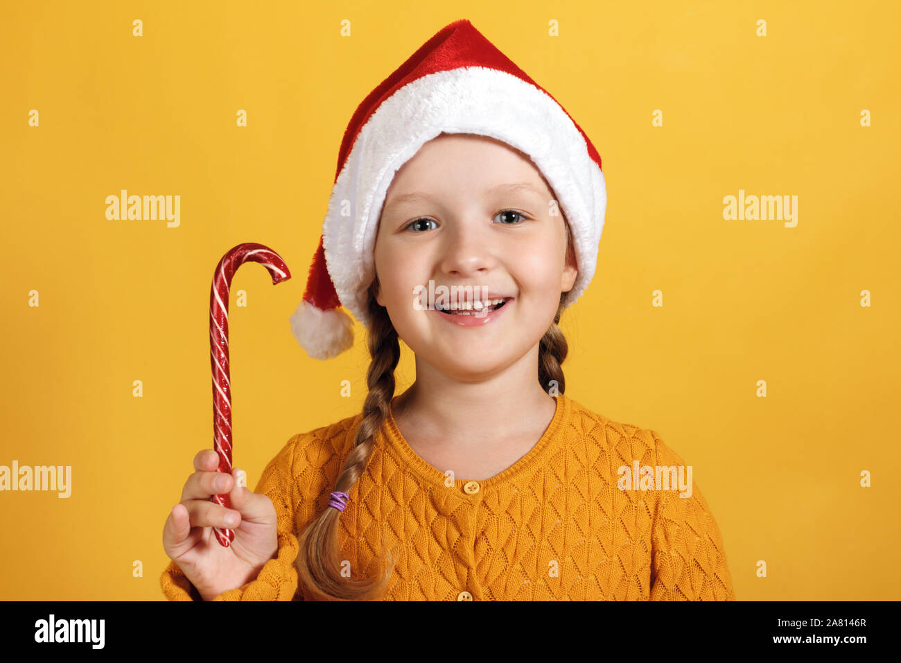 Happy little girl in santa hat with christmas candy. A child on a ...