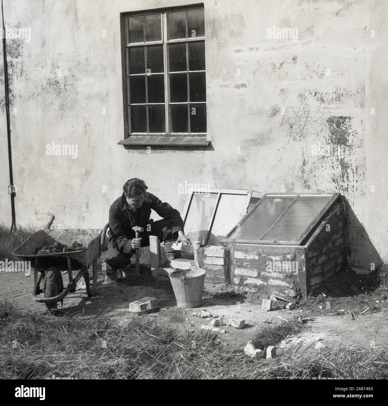 1950s, historical, a tradesman in overalls, outside an old house ...