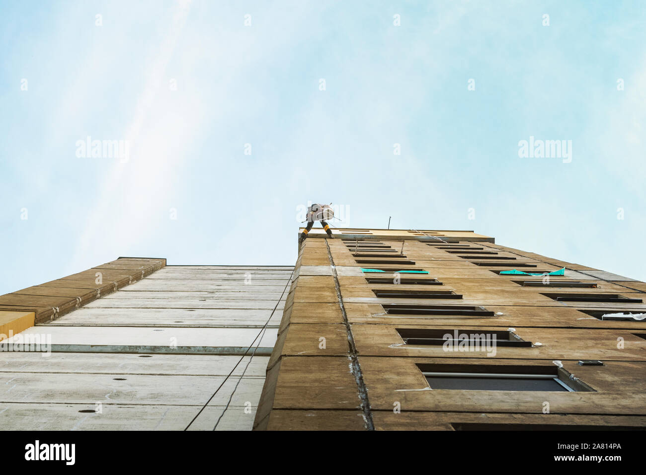 Industrial rope access worker hanging from the building while painting ...