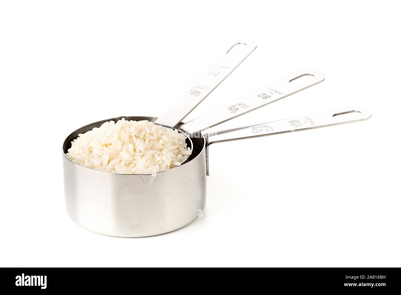 White uncooked, raw long grain rice in metal measurement scoop on white ...