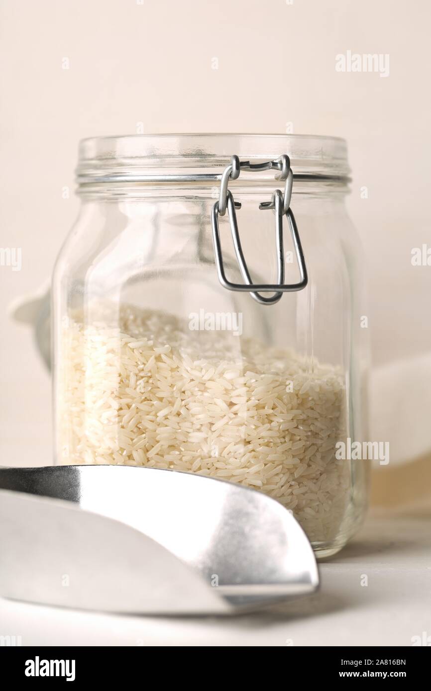 White uncooked, raw long grain rice in glass storage jar with metal ...