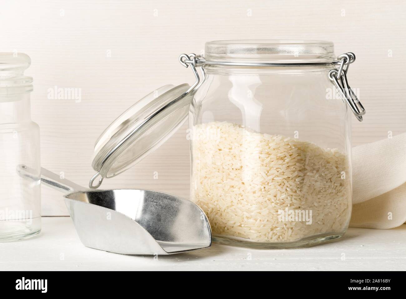 White uncooked, raw long grain rice in glass storage jar with metal ...