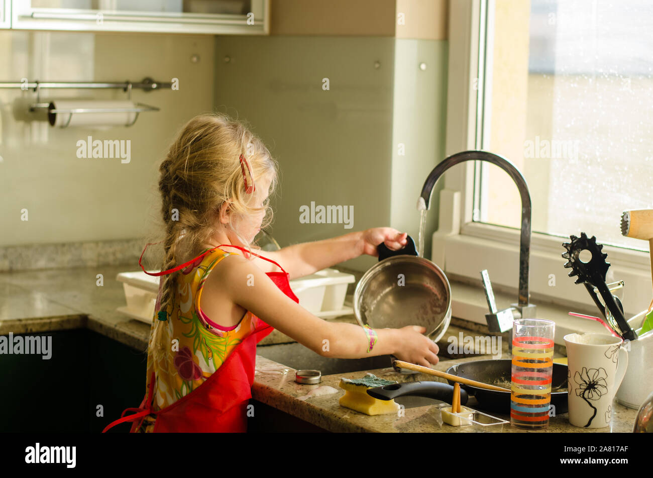 little child washing dishes in the kitchen Stock Photo - Alamy
