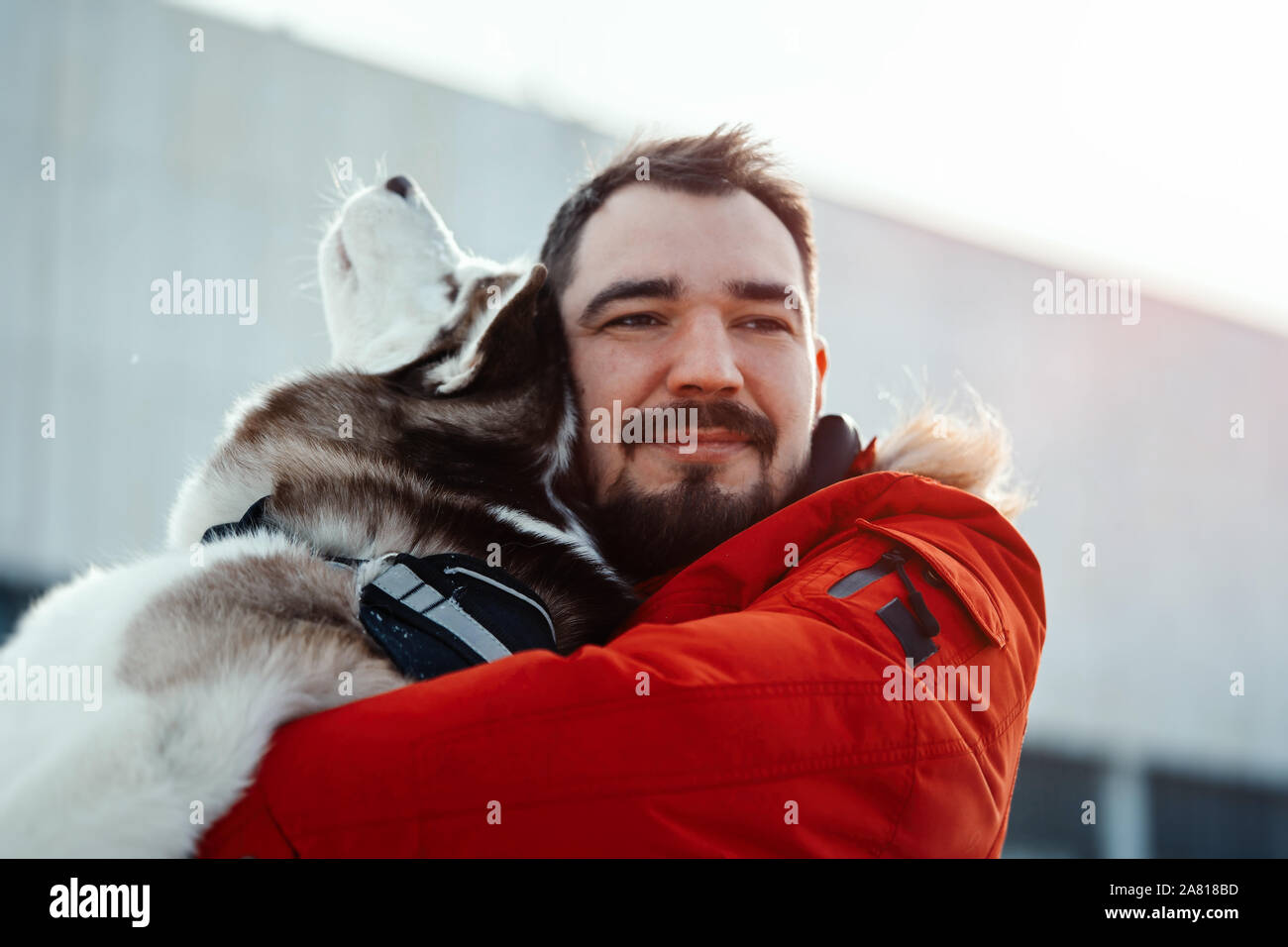 Man hugging Siberian Husky dog on a walk in modern contemporary park on ...