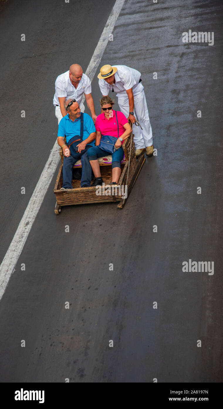Tourists enjoying a traditional basket sled ride in Funchal, Madeira ...