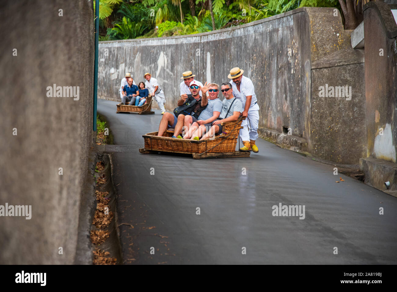 Tourists enjoying a traditional basket sled ride in Funchal, Madeira ...