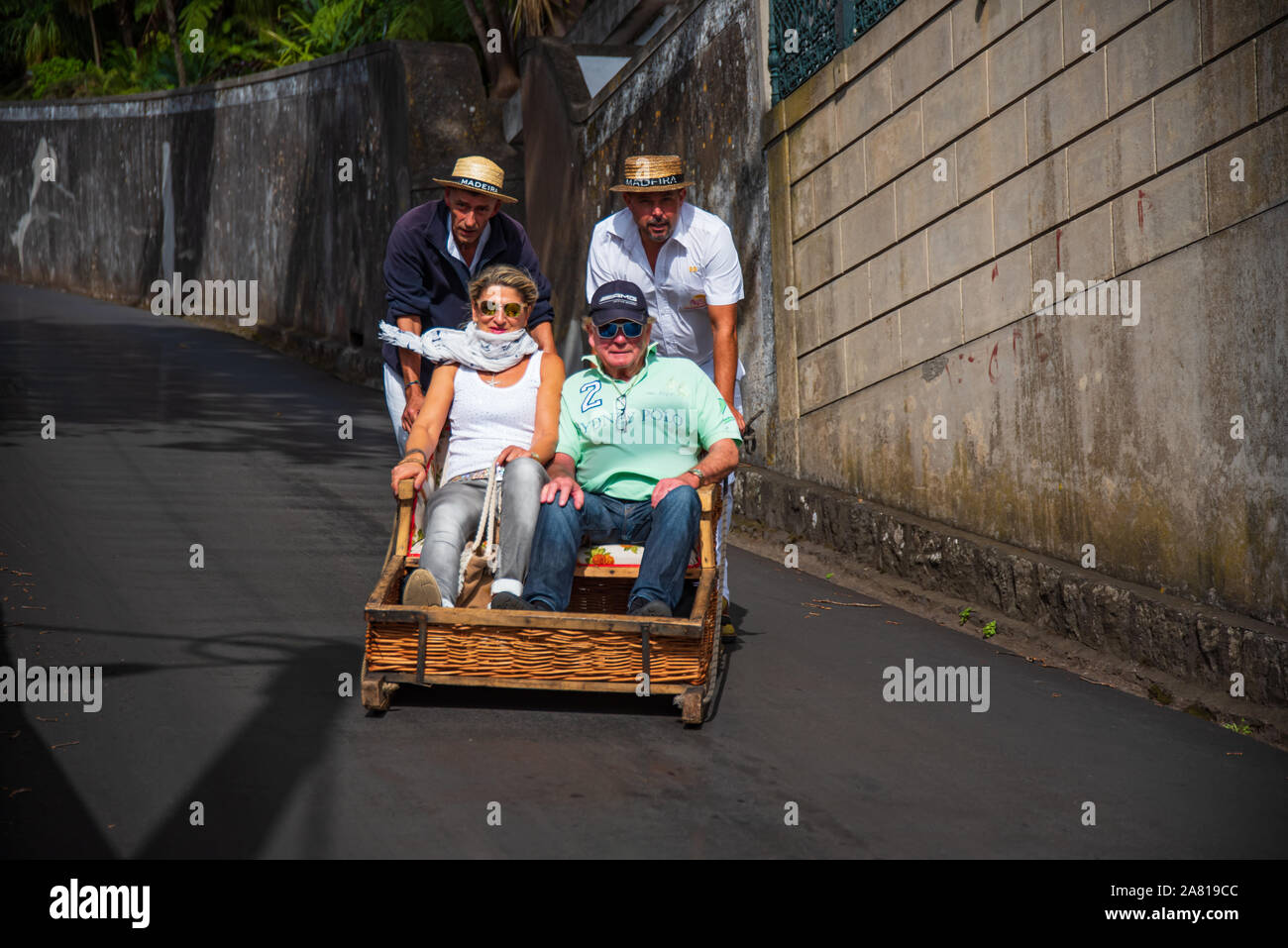 Tourists enjoying a traditional basket sled ride in Funchal, Madeira ...