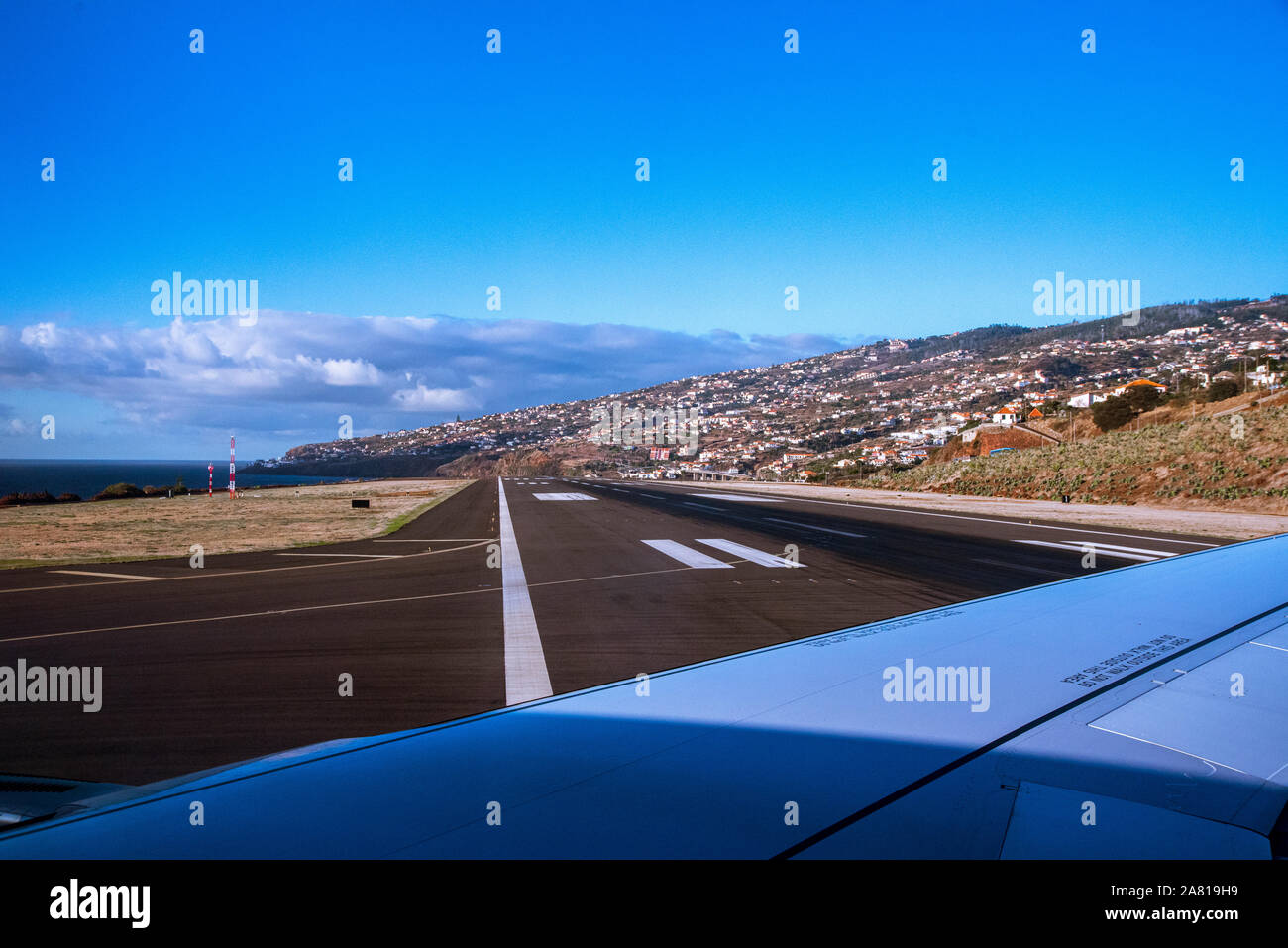 View of Madeira Airport runway from an airplane window, with the island ...