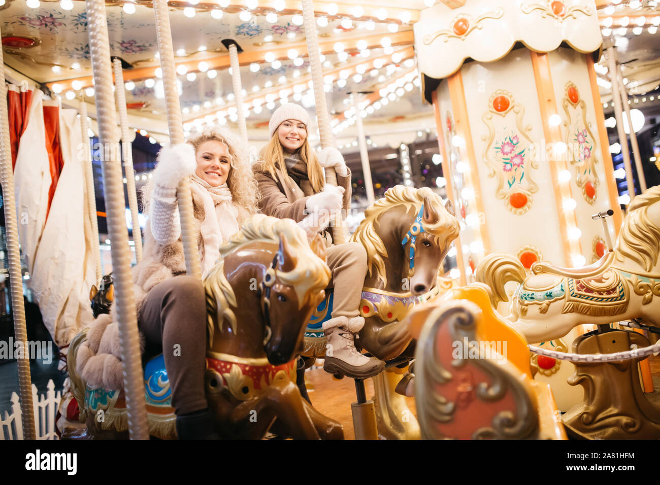 Photo of two women riding on carousel in park at winter evening Stock ...