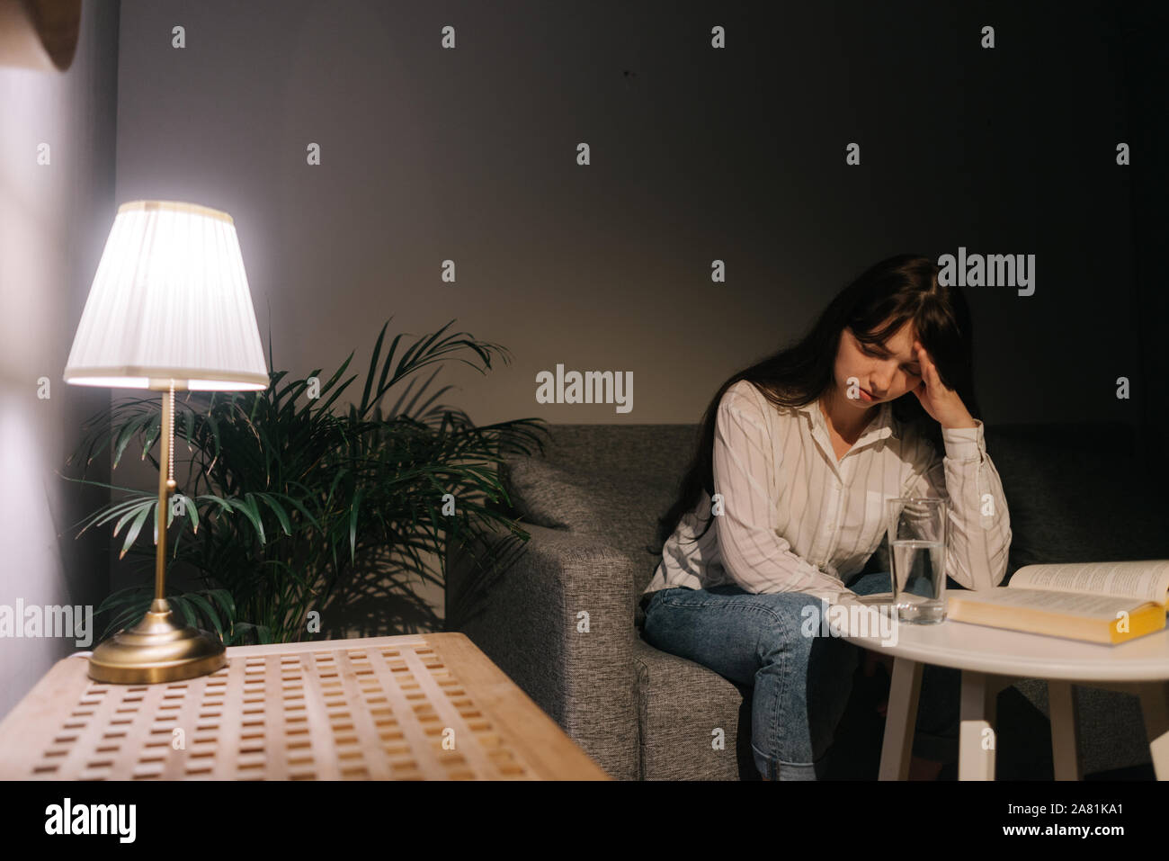 Young woman is thinking in the dark room. Girl sitting on the bed Stock ...