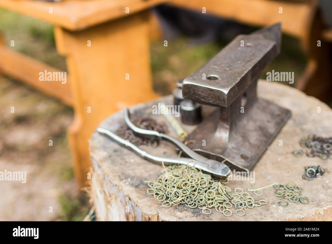 An anvil with tools and lot of rings for chain mail. Close up view ...