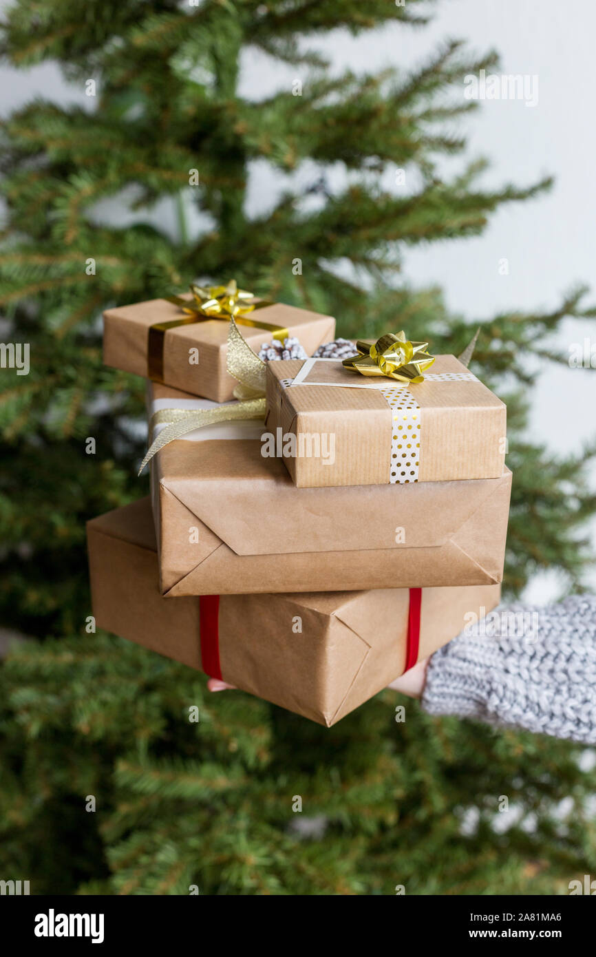 Gifts in hand with Christmas tree behind. Different kind of present ...