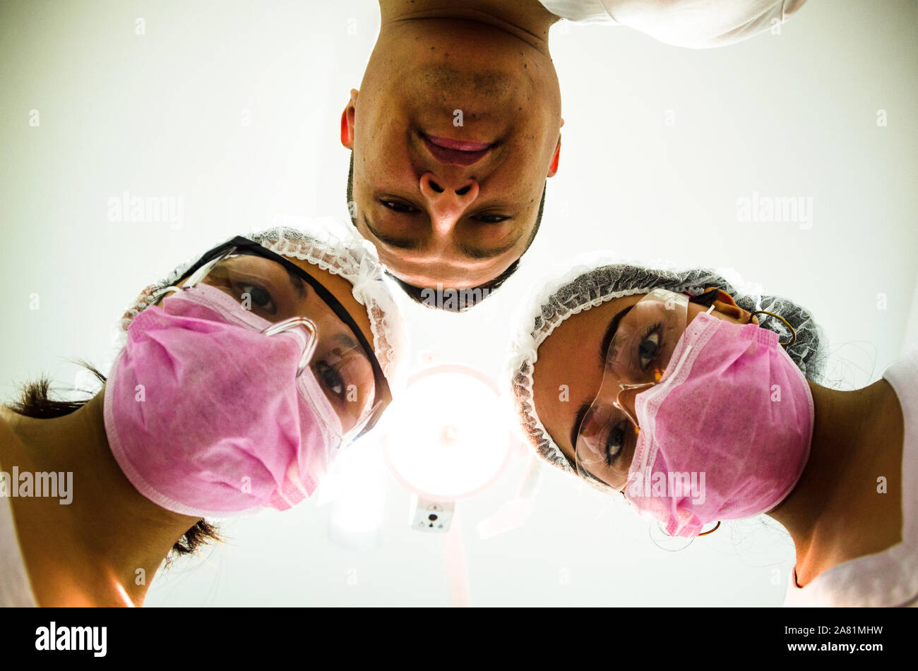 Portrait of three surgeons at work, operating in uniform, looking at ...