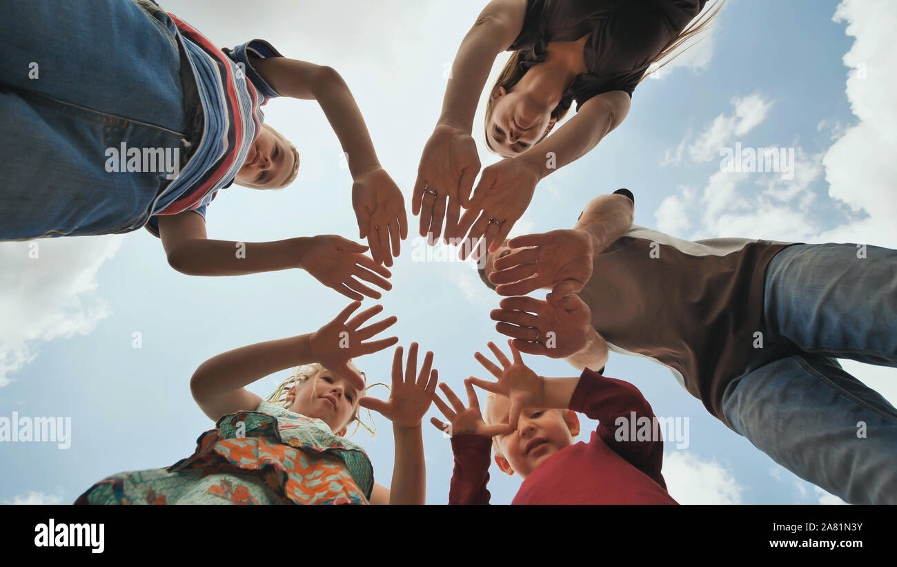 A young family of 6 connects the palms in a circle shape. The concept ...