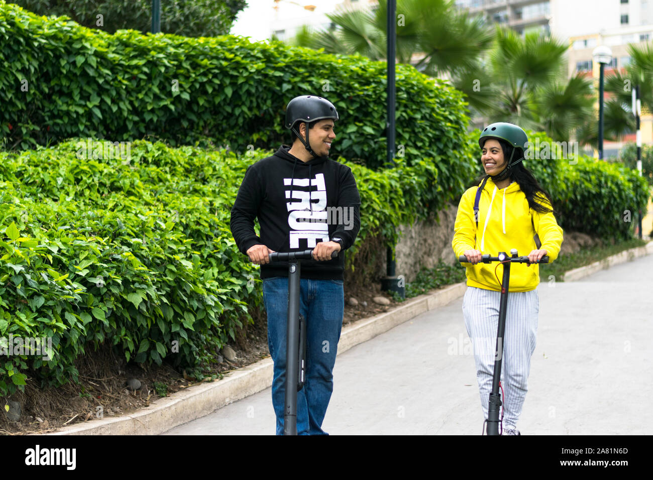Young couple on vacation having fun driving electric scooter through ...