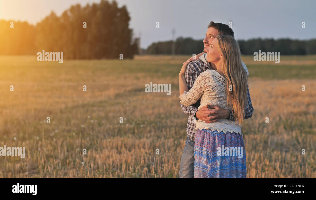 Young husband and wife cuddle at sunset and look towards the sun Stock ...