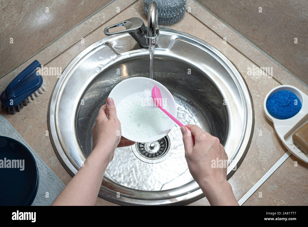 Woman is washing a dishes by the brush in the kitchen sink. Dish ...