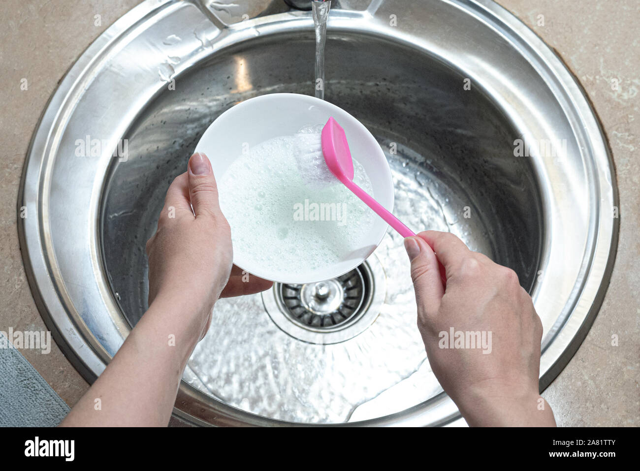 Woman is washing a dishes by the brush in the kitchen sink. Dish ...
