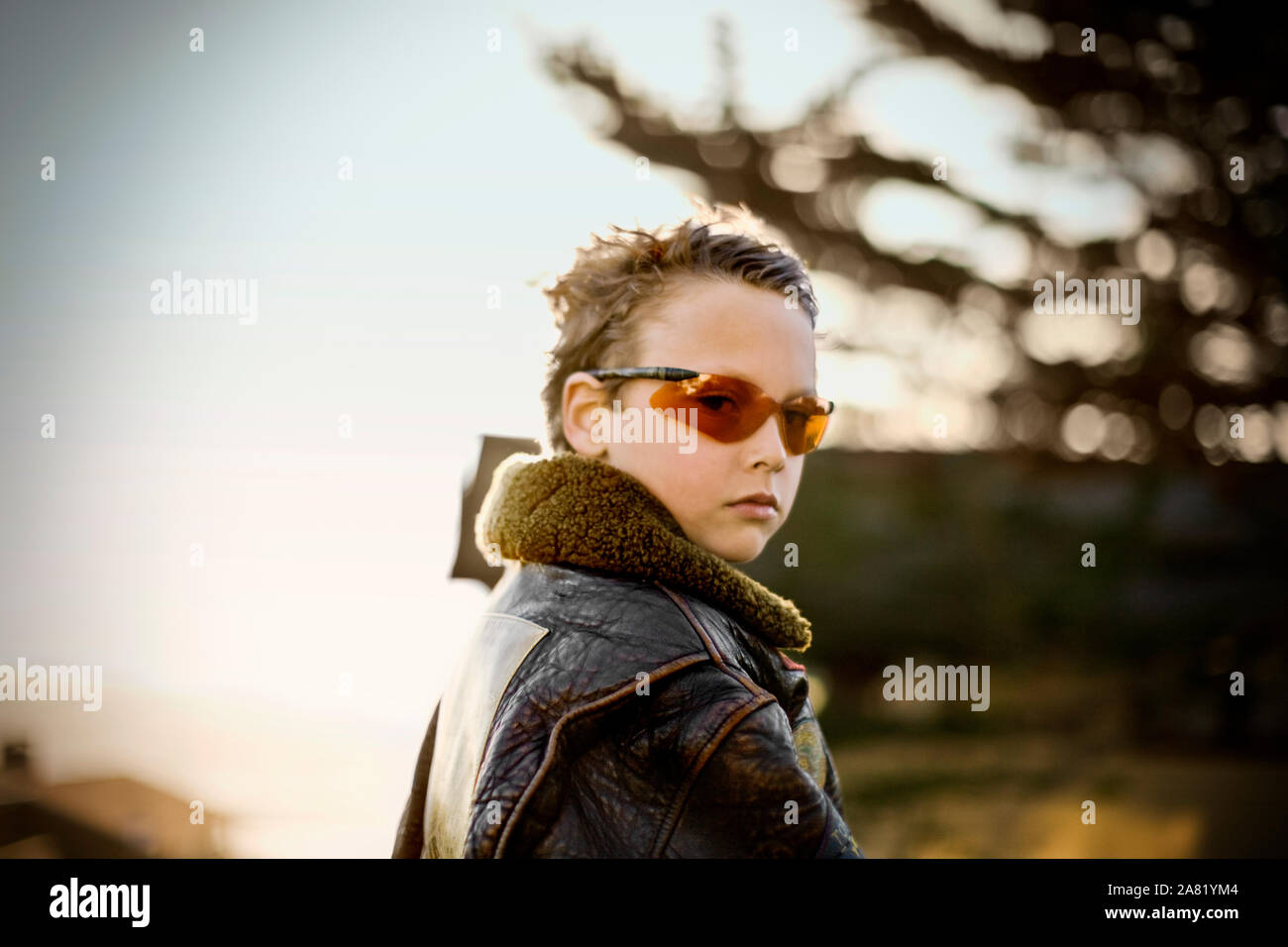Portrait of a young boy looking over his shoulder while wearing tinted ...