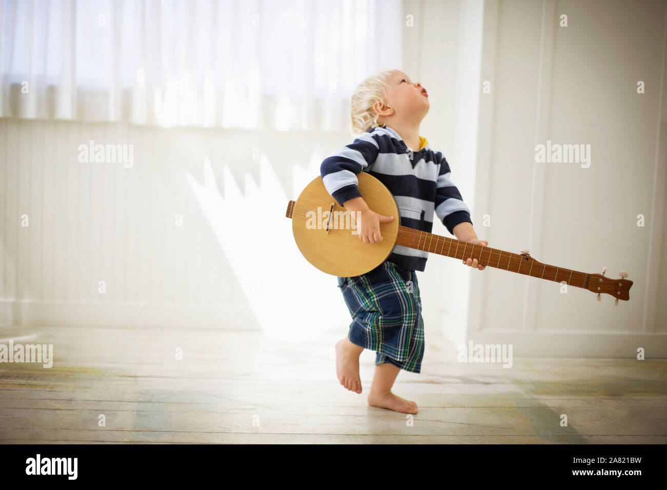 Toddler playing with a wooden banjo Stock Photo - Alamy