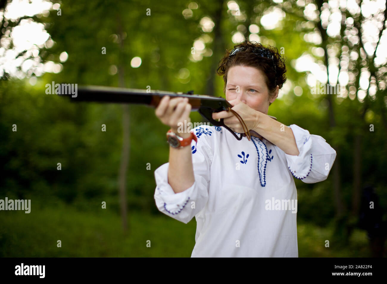 Woman aiming rifle in forest Stock Photo - Alamy