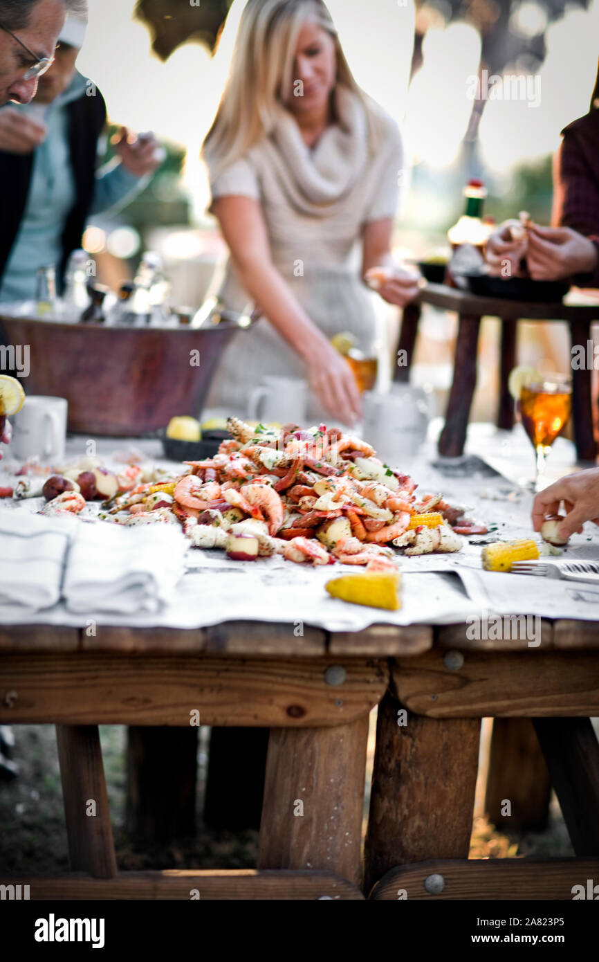 People standing around a table of fresh seafood at an outdoor dinner ...