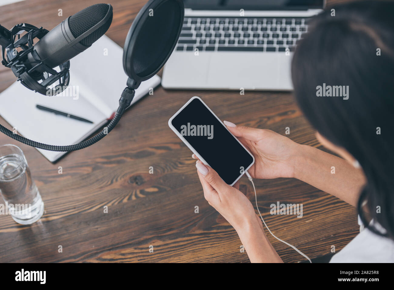 overhead view of radio host holding smartphone with blank screen while ...