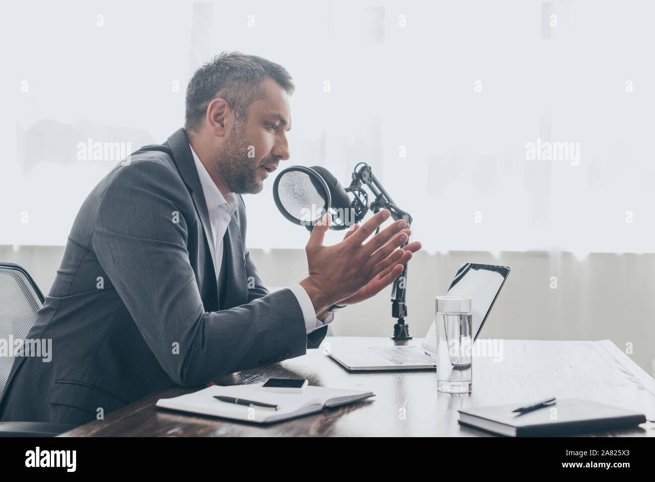 handsome serious radio host speaking in microphone in broadcasting ...