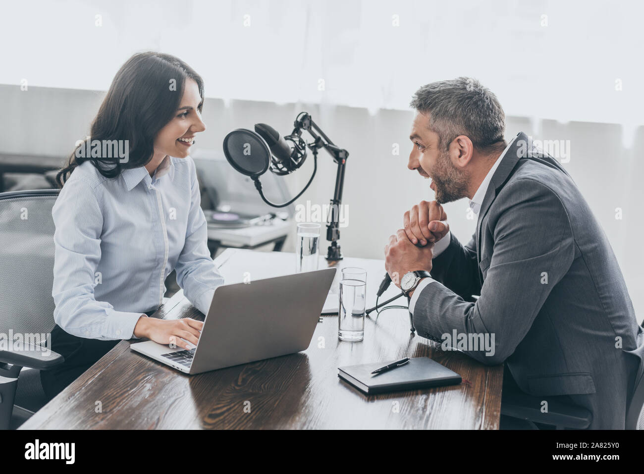 cheerful radio host and businessman talking in broadcasting studio ...