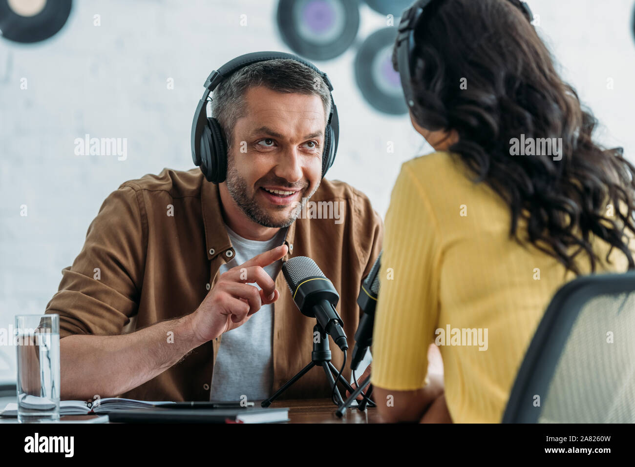 smiling radio host gesturing while talking to colleague in broadcasting ...