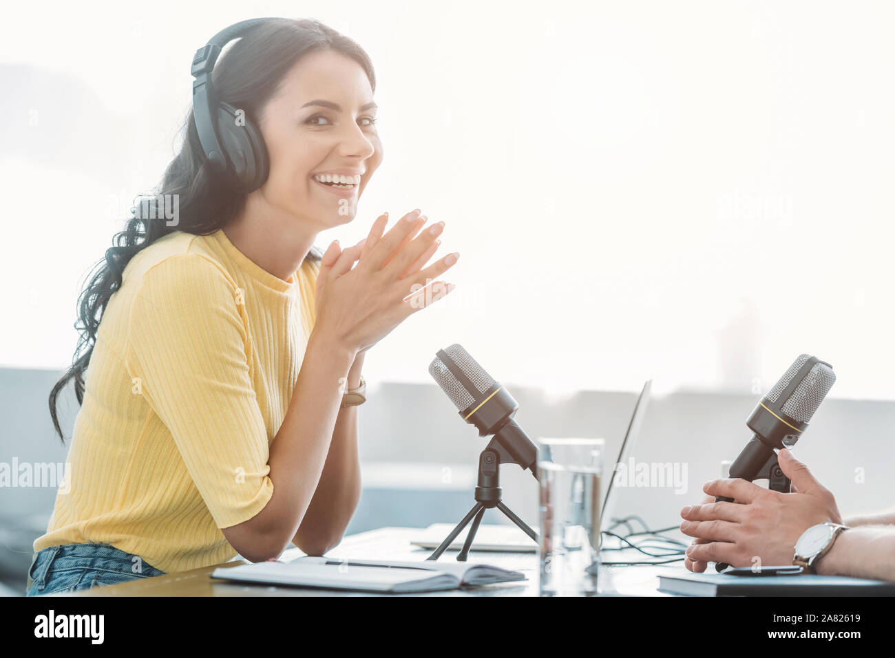 cheerful radio host looking at camera while sitting near colleague in ...