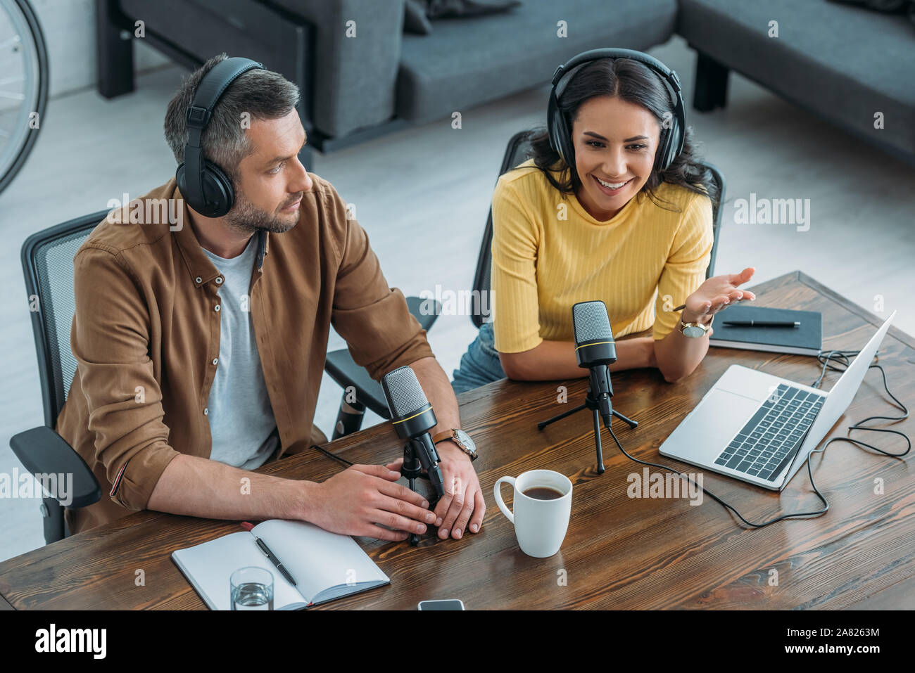 pretty radio hosts talking in microphone while sitting at workplace ...