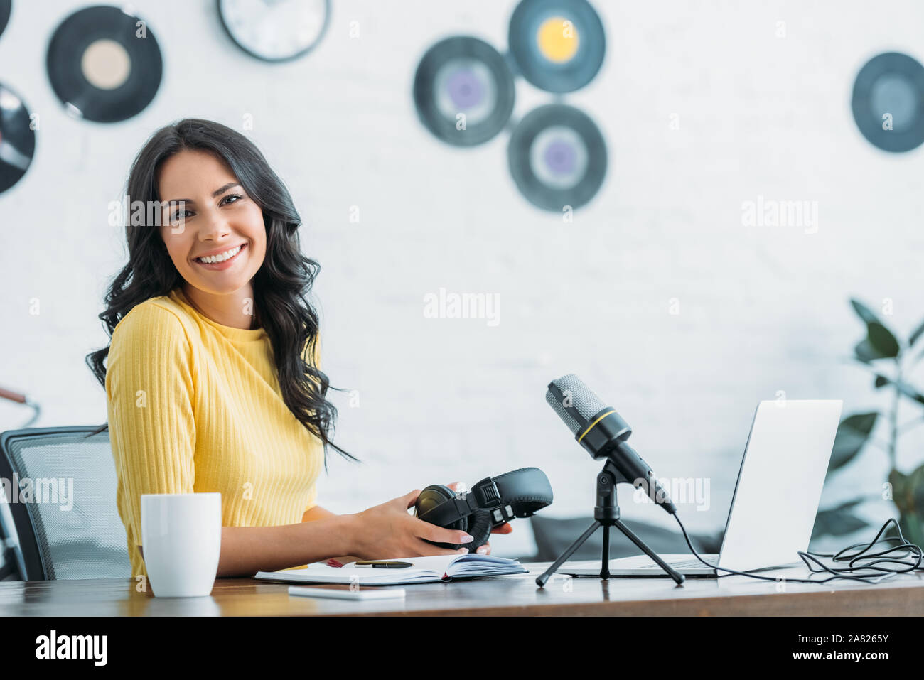 cheerful radio host smiling at camera while sitting at workplace and ...