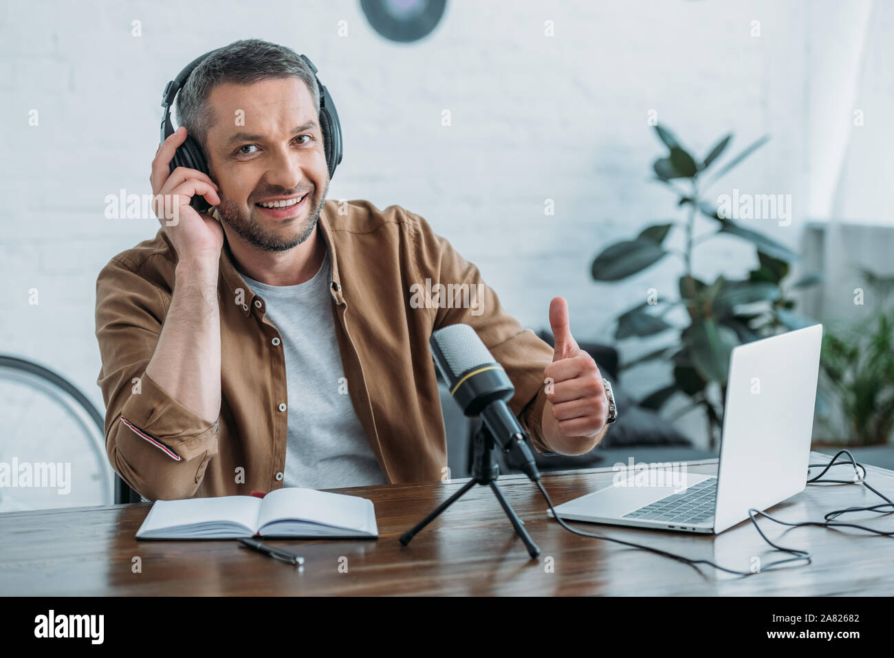 handsome radio host showing thumb up and smiling at camera while ...