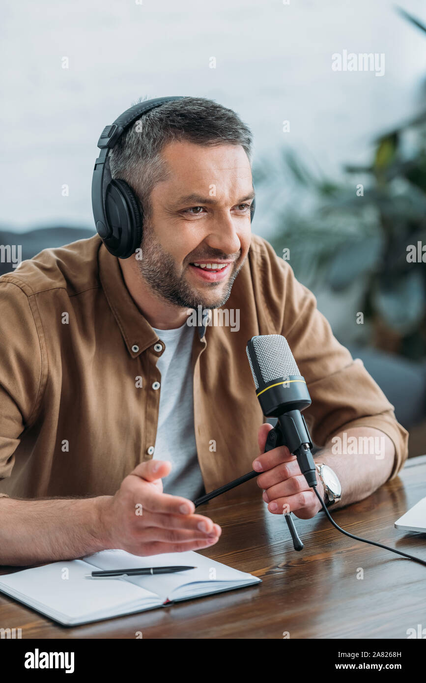 handsome radio host in headphones gesturing while speaking in ...