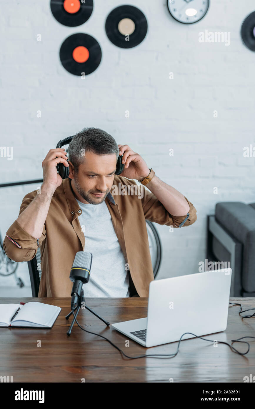 handsome radio host holding putting on headphones while looking at ...