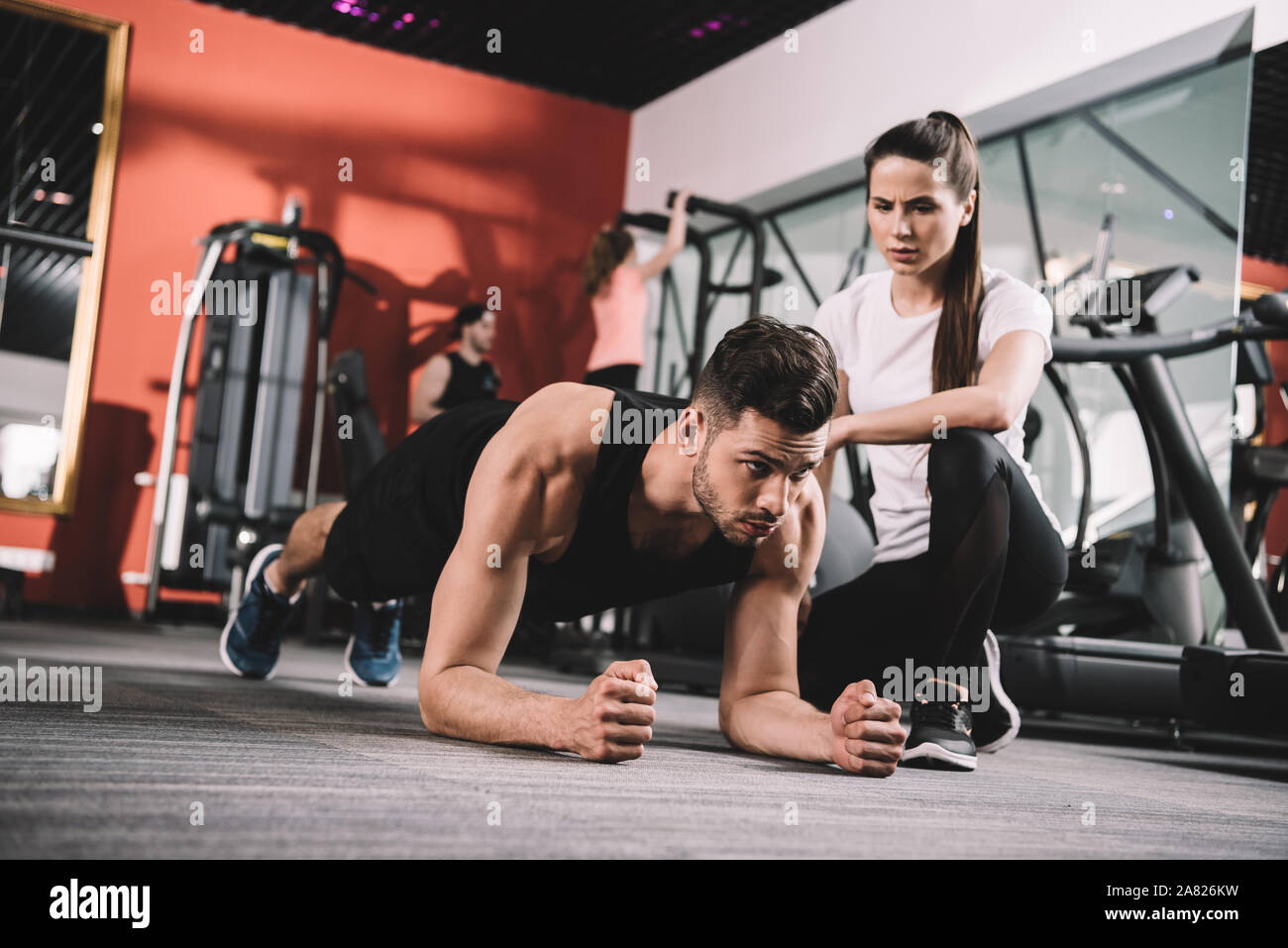 attractive trainer supervising sportsman doing plank exercise Stock ...