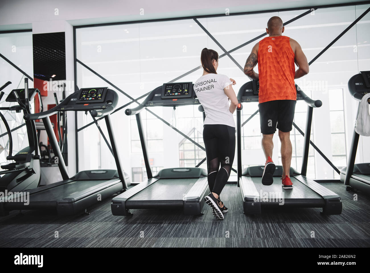 back view of personal trainer supervising african american sportsman ...