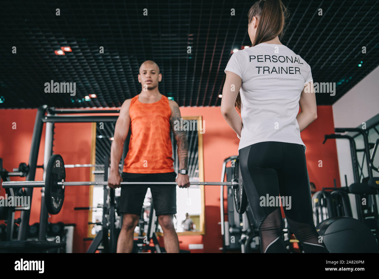 back view of personal trainer standing near african american athlete ...