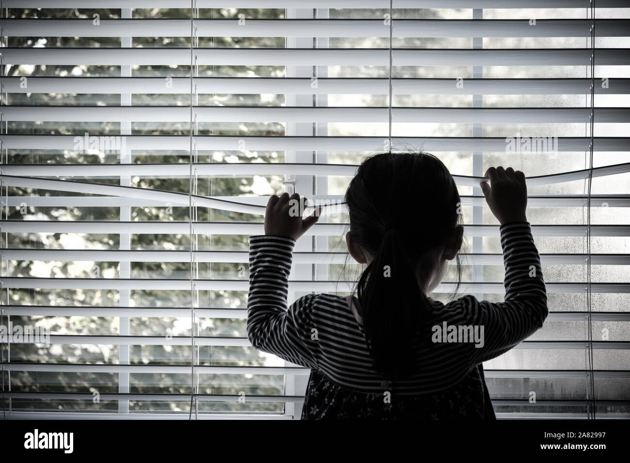 Lonely little kid in front of a window Stock Photo - Alamy