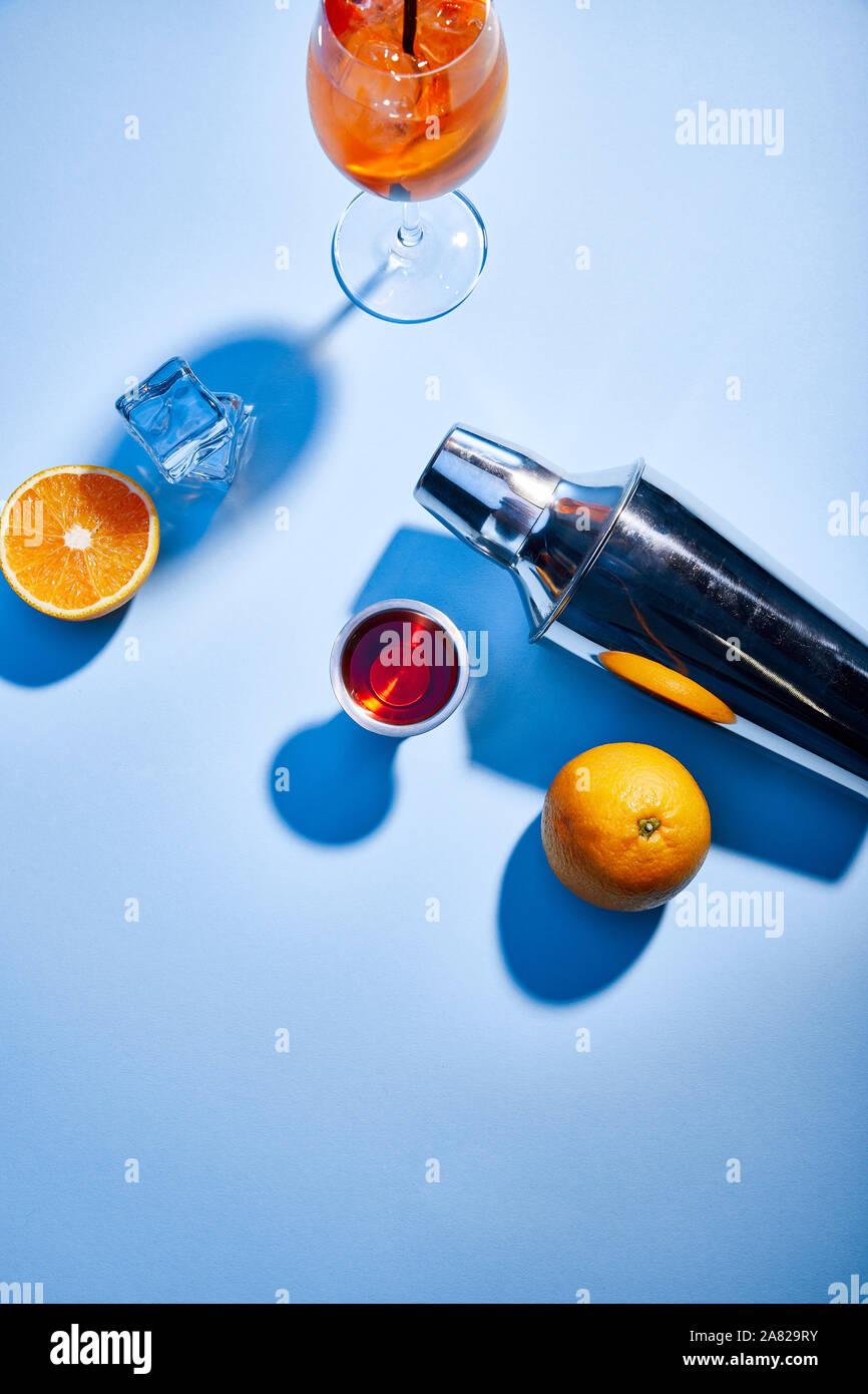top view of Aperol Spritz, oranges, shaker, ice cubes and measuring cup ...