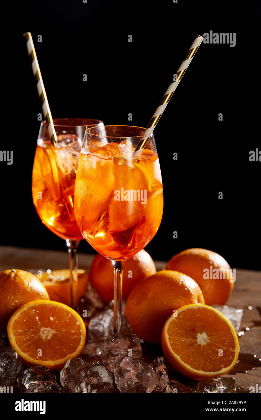 Aperol Spritz in glasses, oranges and ice cubes on black background ...
