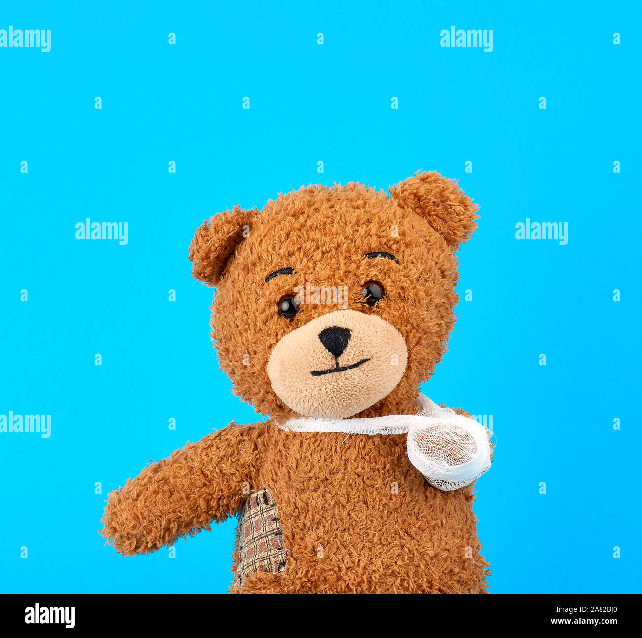 Brown Teddy Bear With A Bandaged Paw Sitting On A Blue Background