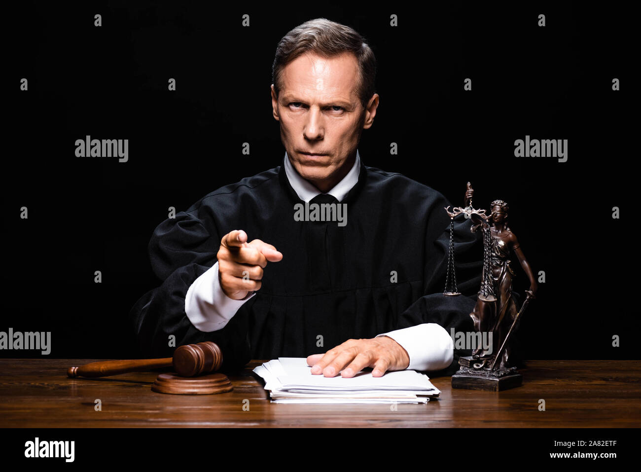 judge in judicial robe sitting at table and pointing with finger ...