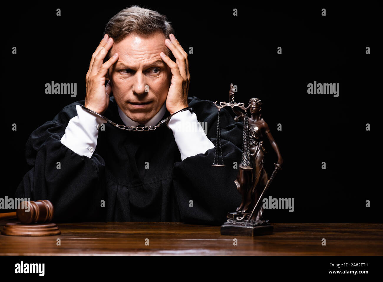 judge in judicial robe sitting at table with handcuffs isolated on ...