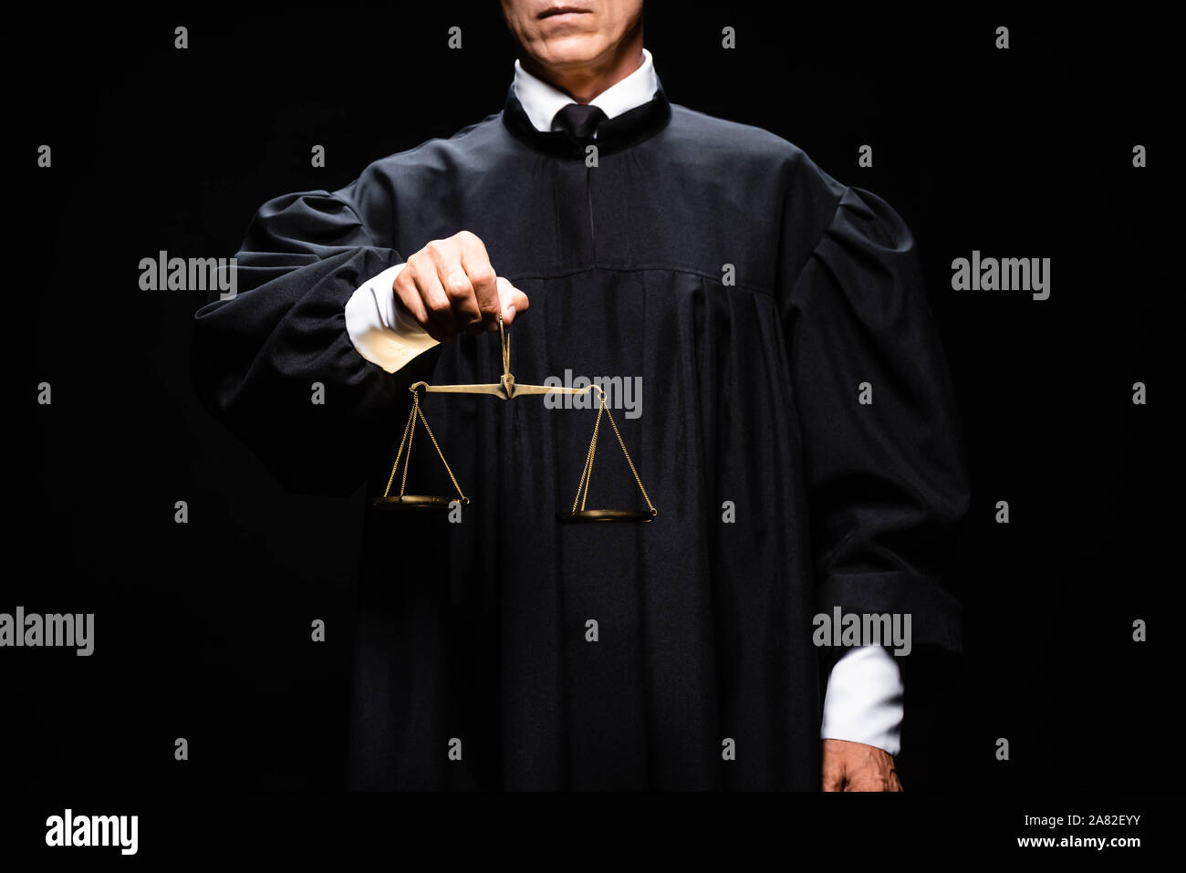 cropped view of judge in judicial robe holding scales of justice ...